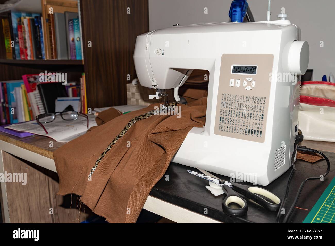 Close-up view of working sewing machine sewing brown fabric Stock Photo ...