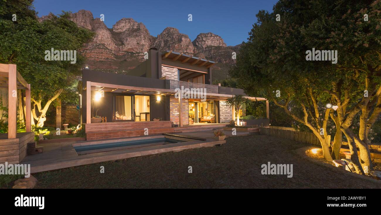 Mountains behind illuminated modern, luxury home showcase exterior ...