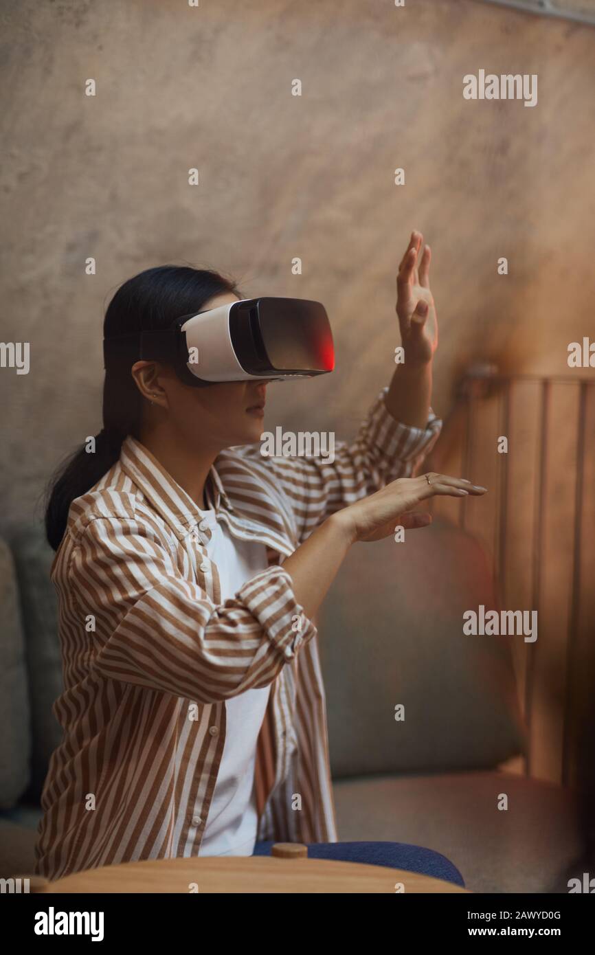 Side view portrait of Asian woman wearing VR gear and gesturing while ...