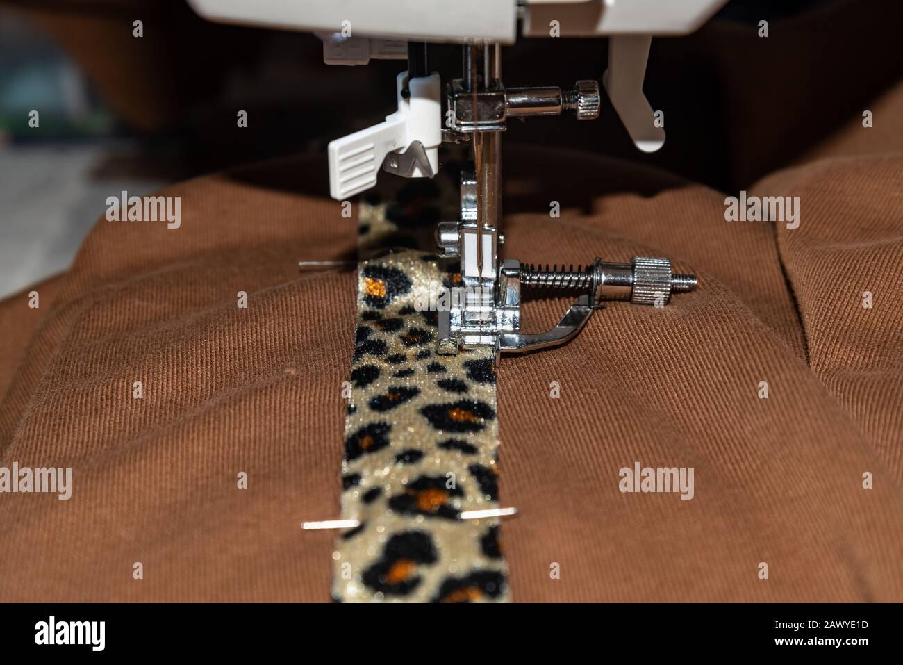 Close-up view of working sewing machine sewing brown fabric Stock Photo ...