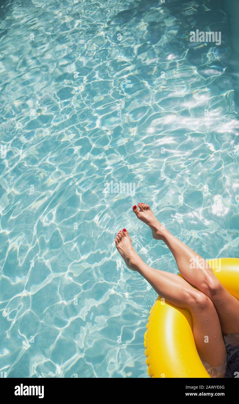 Woman with bare feet relaxing, floating in inflatable ring in sunny ...