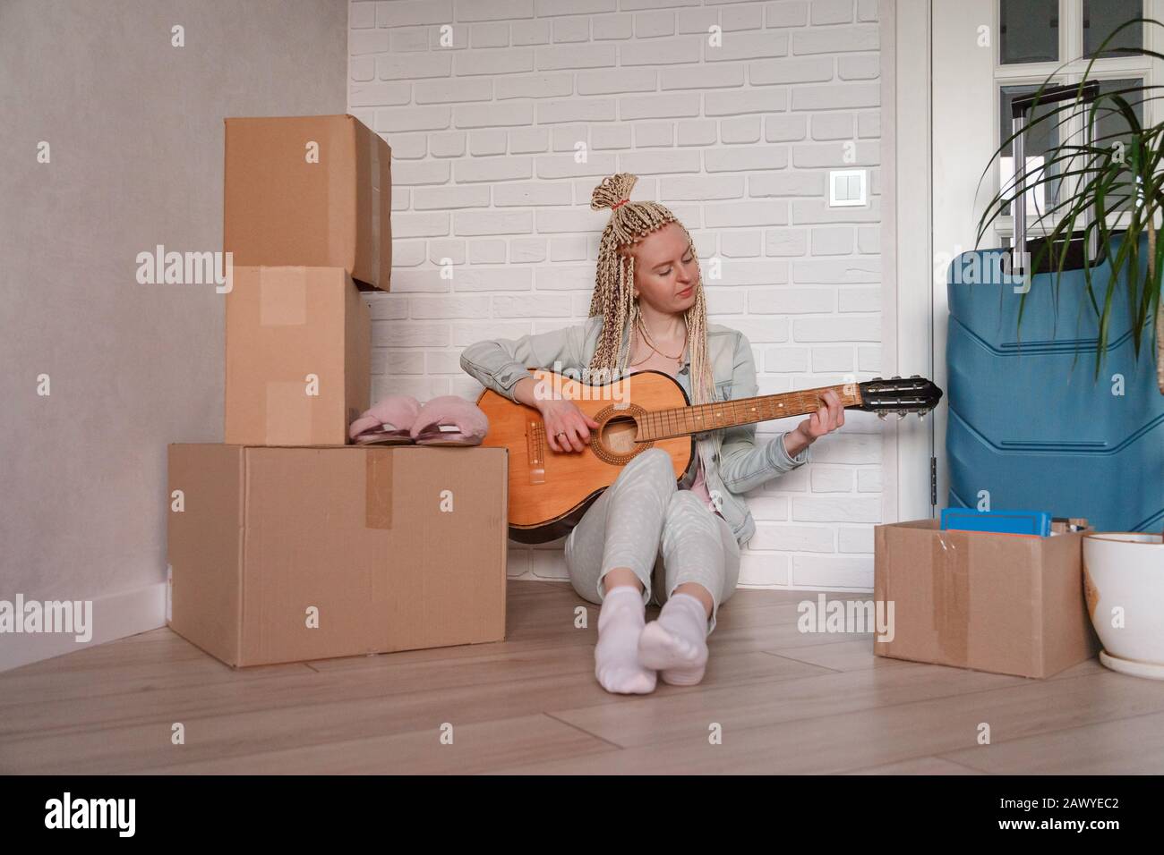 An attractive young woman is sitting on a couch and playing the guitar ...
