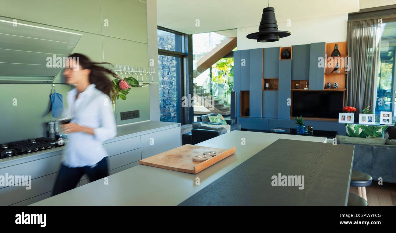 Woman walking in modern kitchen Stock Photo - Alamy
