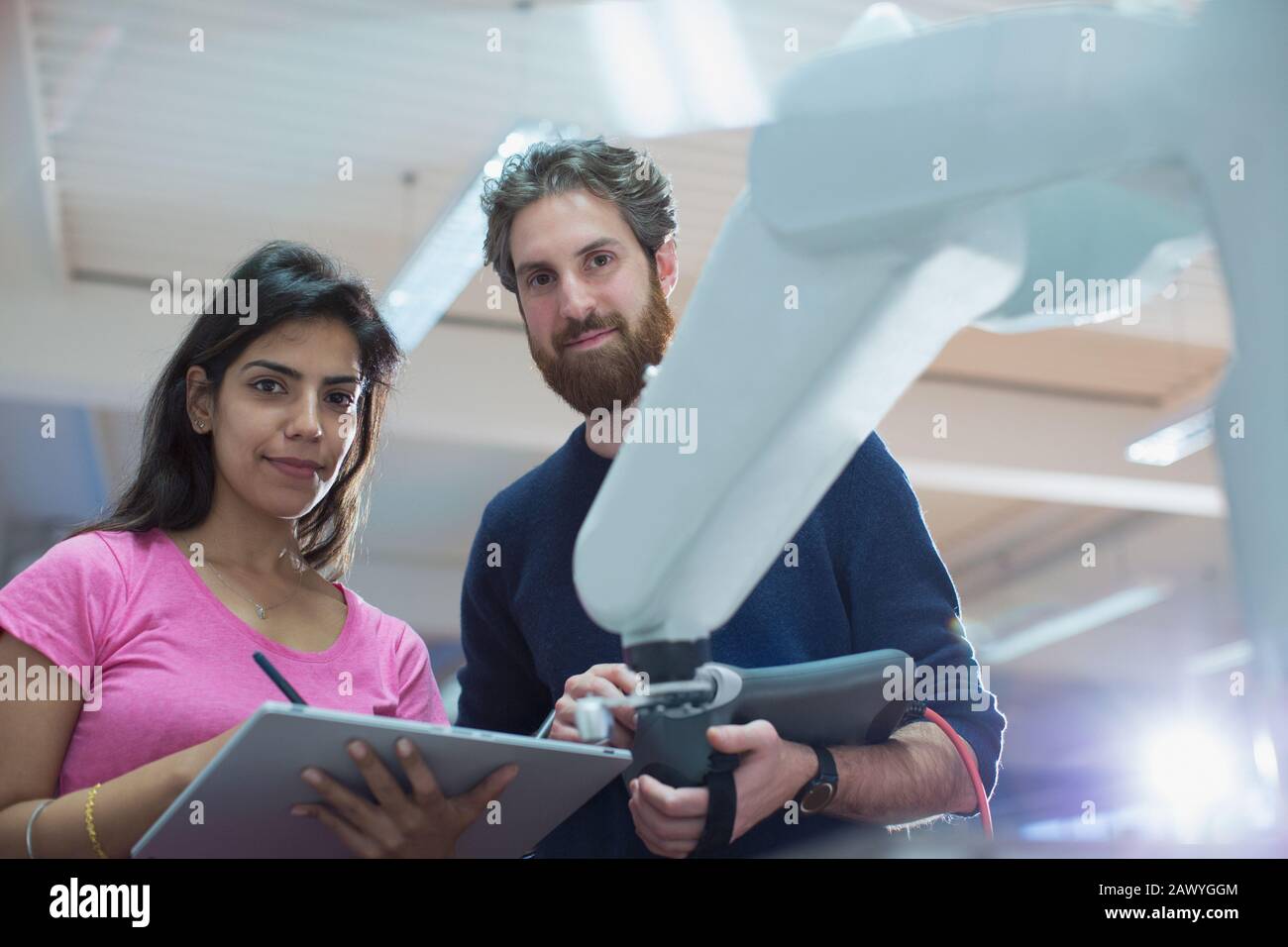 Portrait confident engineers with digital tablet programming robotic ...
