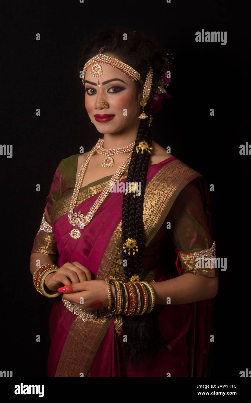 An Indian bride wearing red saree, braided hair and gold jewelry ...