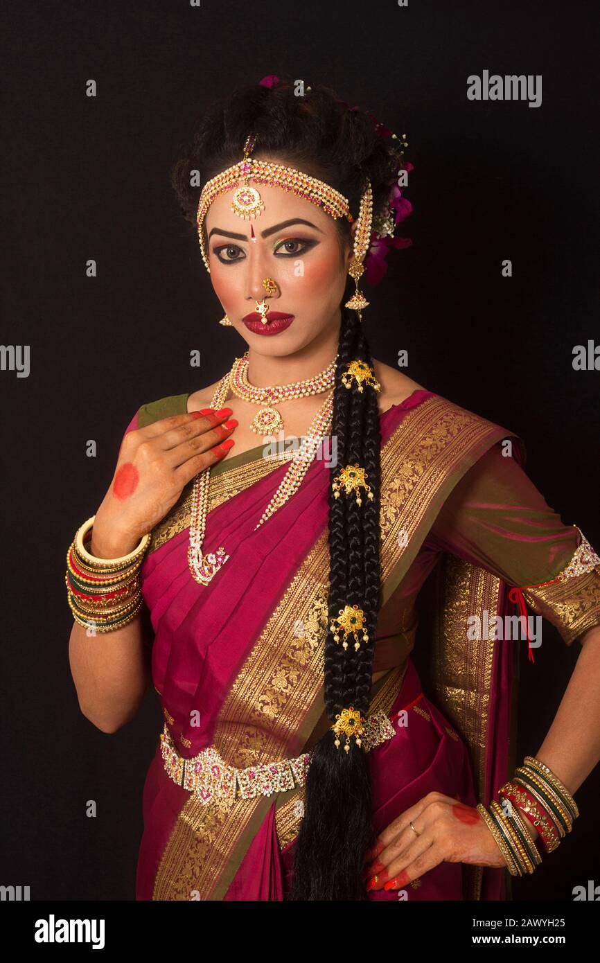 An Indian bride wearing red saree, braided hair and gold jewelry ...