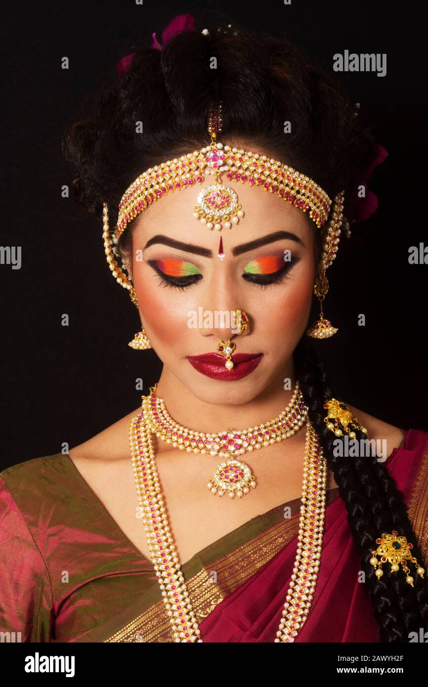 An Indian bride wearing red saree, braided hair and gold jewelry ...