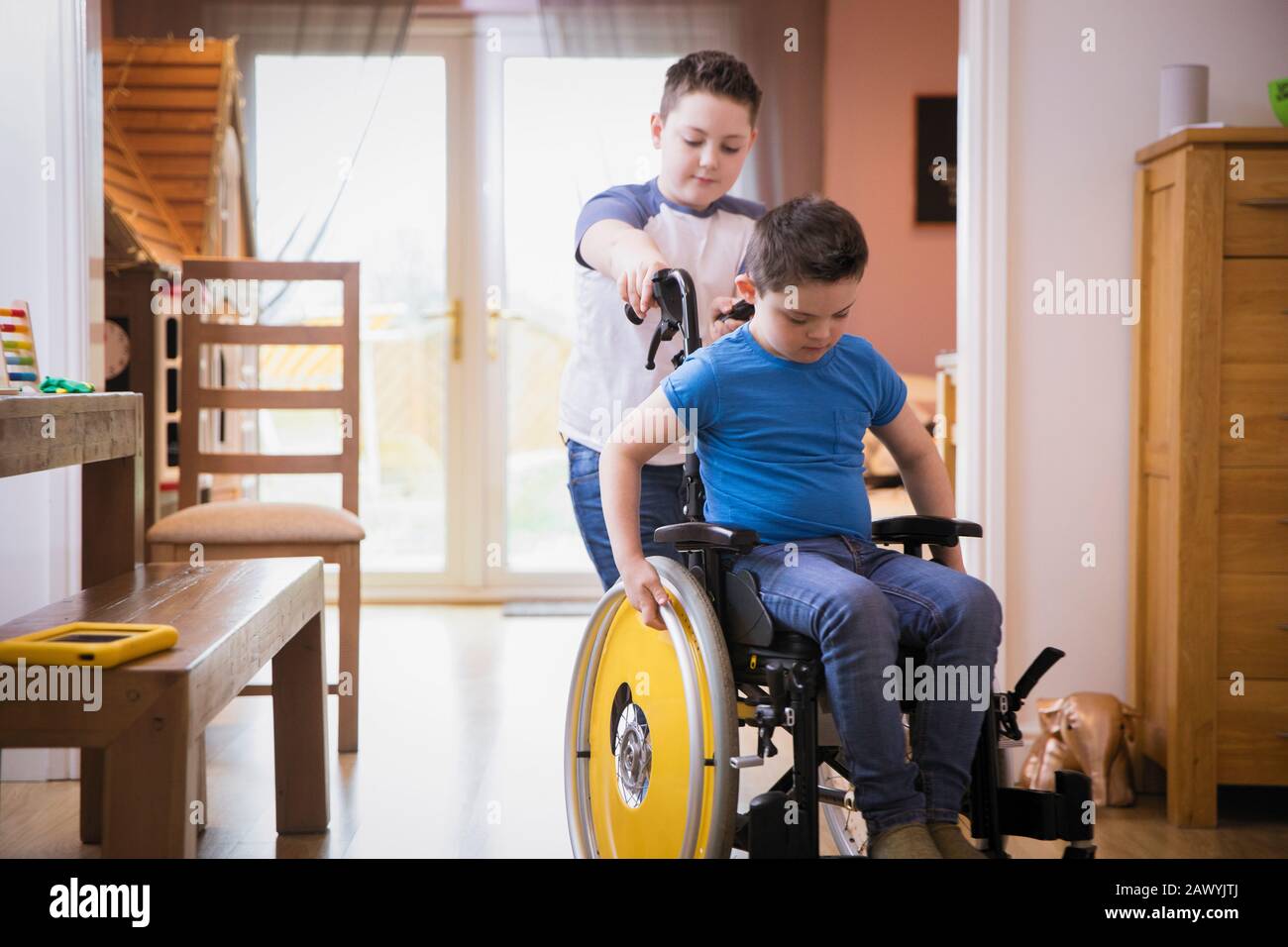 Boy pushing brother with Down Syndrome in wheelchair Stock Photo - Alamy