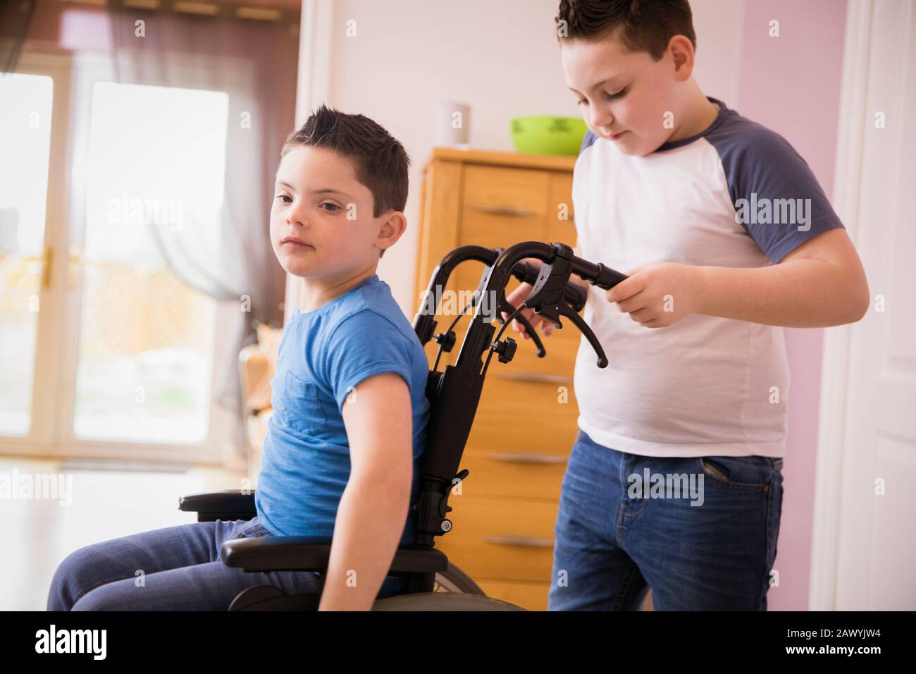 Boy pushing brother with Down Syndrome in wheelchair Stock Photo - Alamy