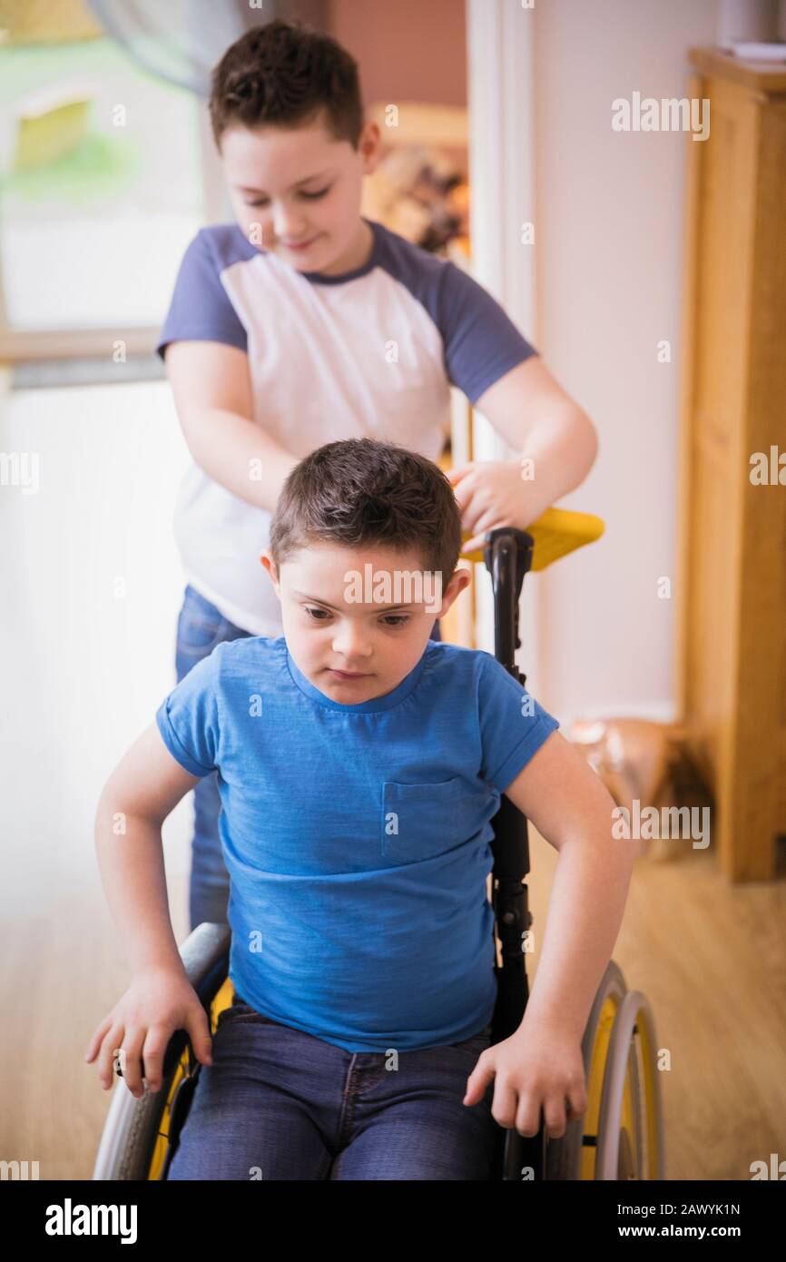 Boy pushing brother with Down Syndrome in wheelchair Stock Photo - Alamy