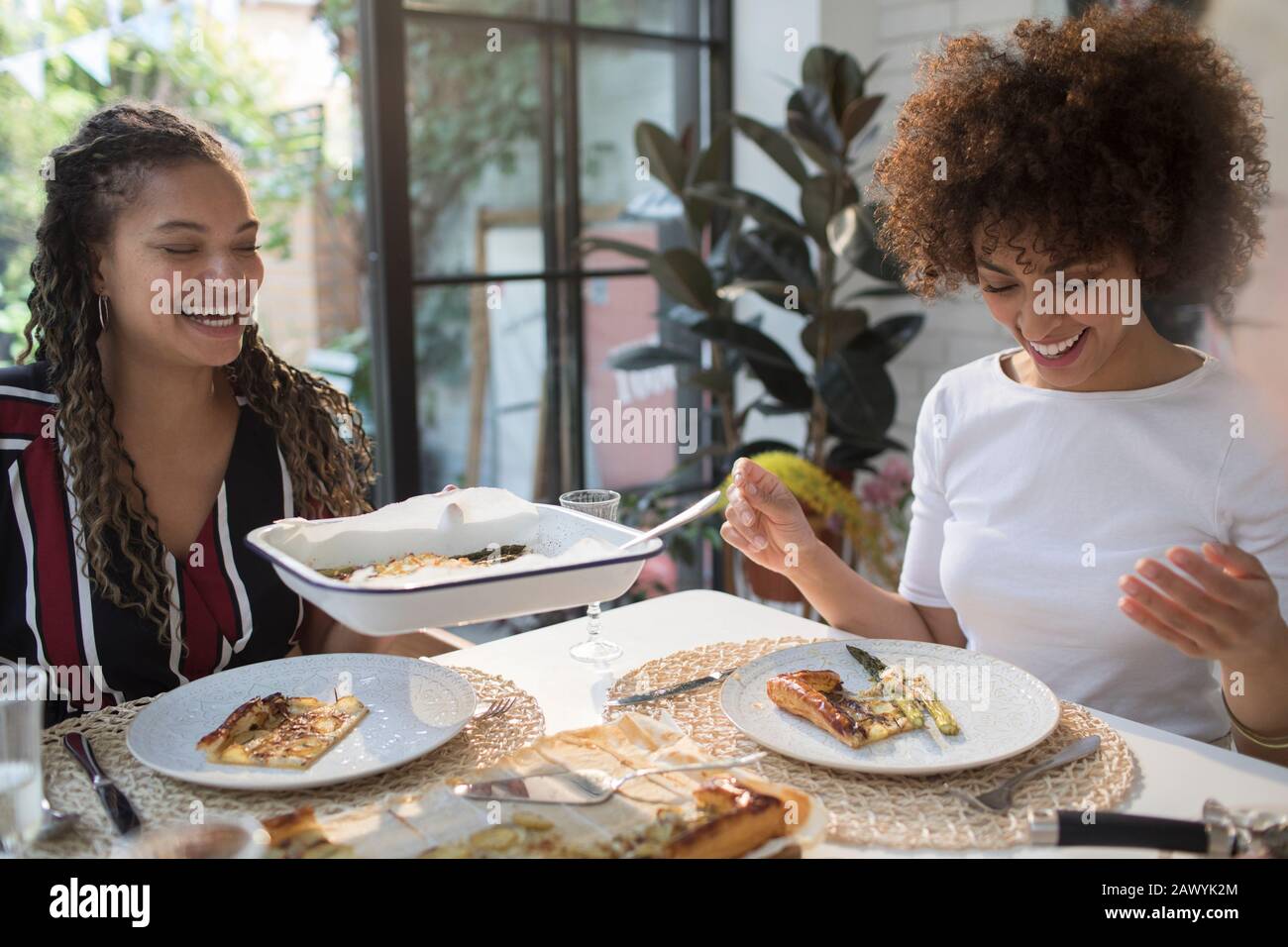 Happy young women eating lunch at dining table Stock Photo - Alamy