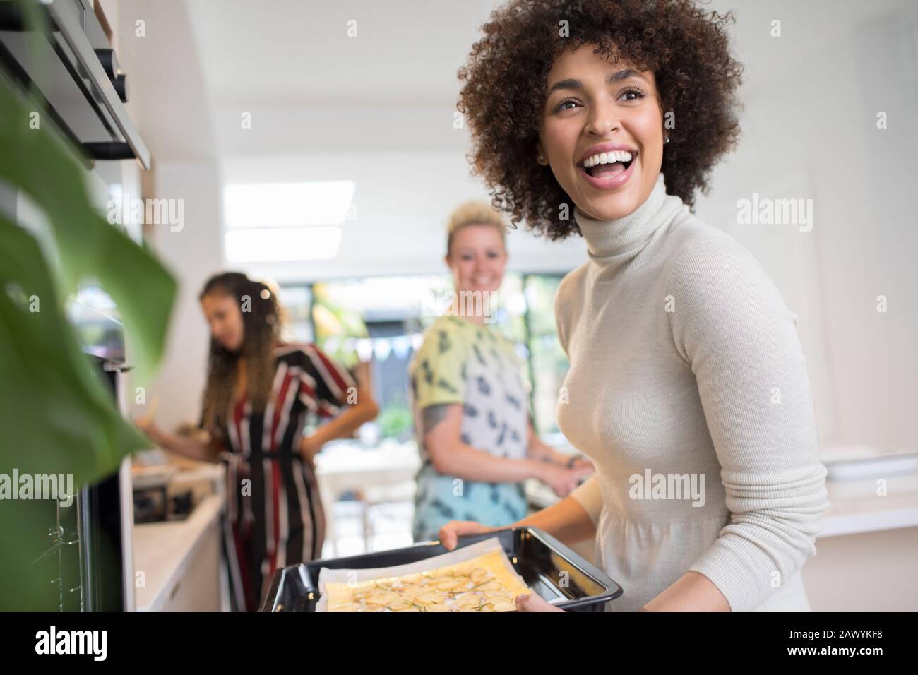 Happy young woman cooking with friends in kitchen Stock Photo - Alamy