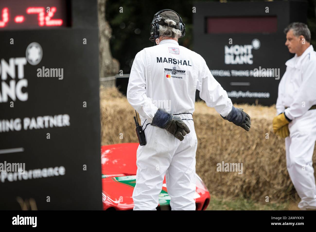 A race marshal holds out an arm to stop a racing car on the starting ...
