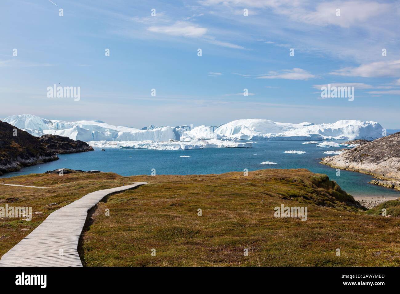Sunny footpath leading to beach overlooking icebergs Greenland Stock ...