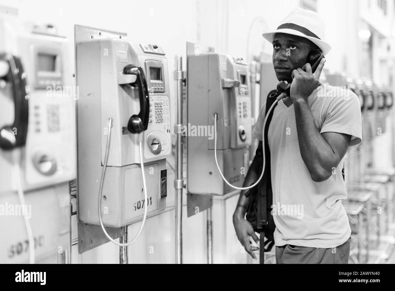 Young African tourist man talking on payphone while thinking inside the ...