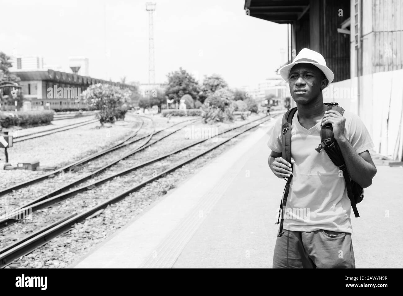 Young African tourist man thinking while waiting for the train against ...