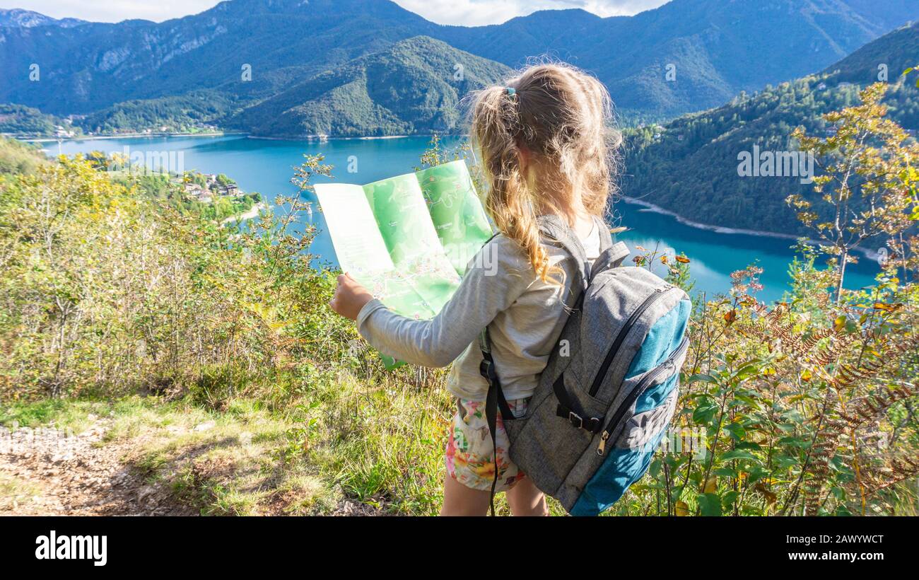 An independent blonde girl with a tourist backpack lays a route on a ...