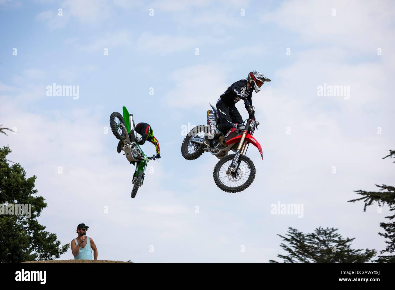 Two motorcycle riders jumping high in the air during a demonstration ...