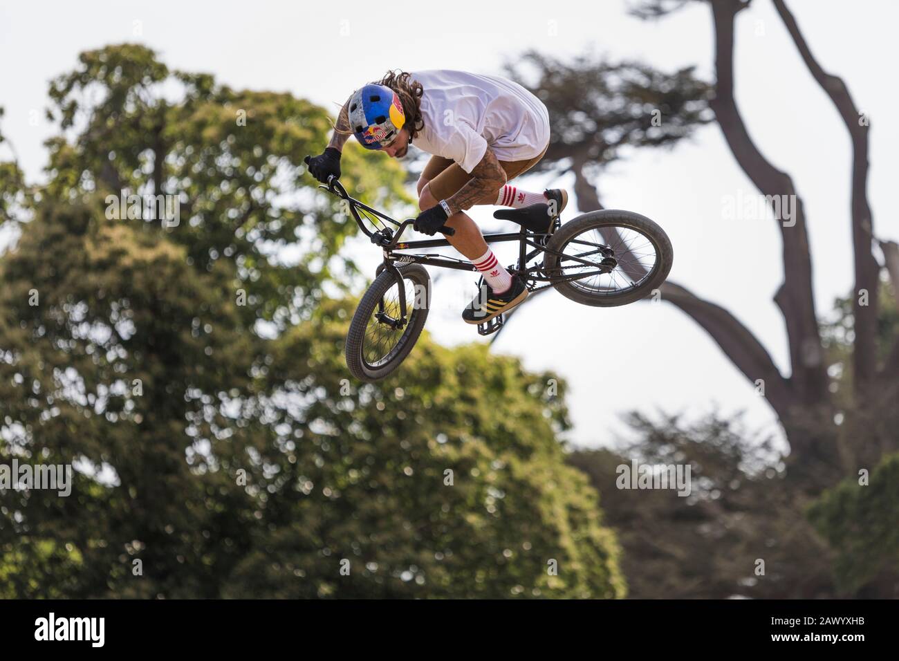 BMX rider with arm tattoos jumping high in the air during a ...