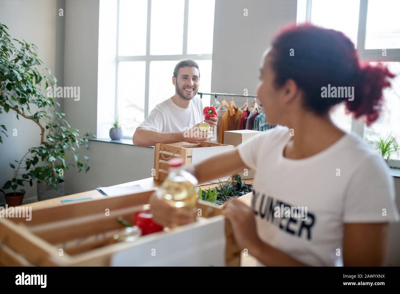 Young man, girl packing up donation boxes looking at each other Stock ...