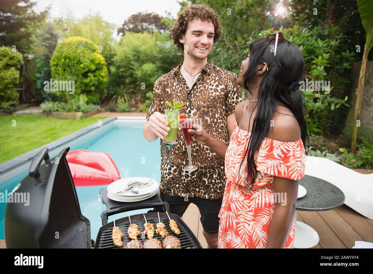 Happy young couple drinking cocktails at poolside barbecue Stock Photo ...