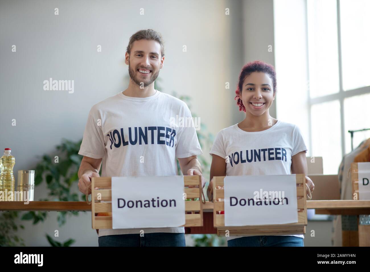 Young volunteers standing with boxes for charity help in their hands ...