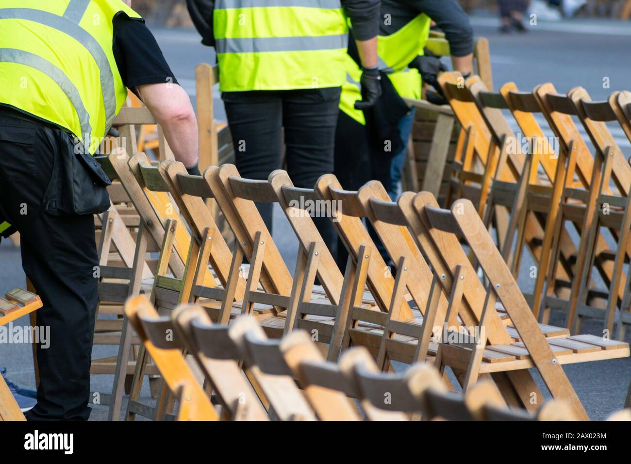 Closeup shot of security guards in yellow uniforms arranging chairs for ...