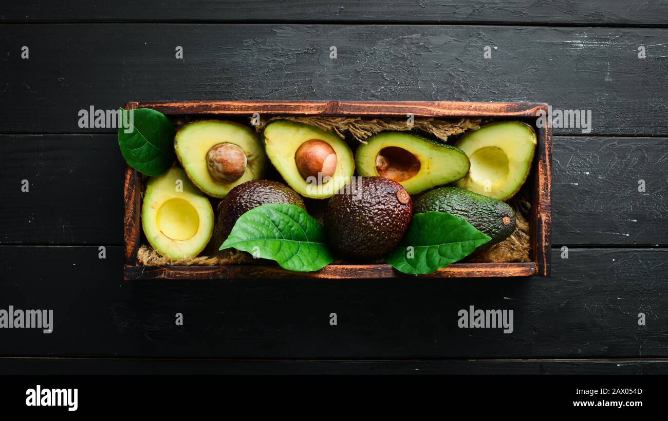Avocado with leaves in the box. Rustic style. Top view. Free space for ...