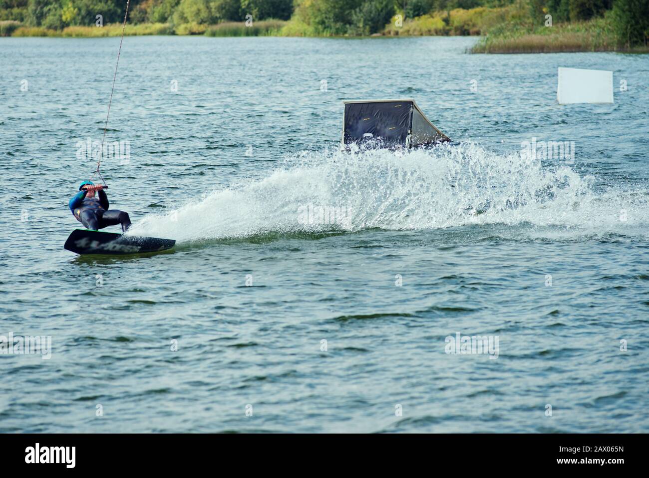 Wakeboarder making tricks. Low angle shot of man wakeboarding on a lake ...