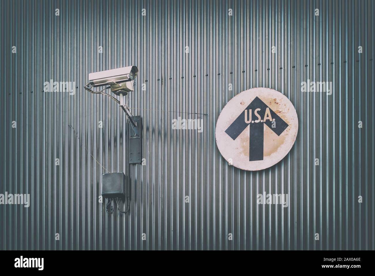 Surveillance camera with vintage USA direction sign on a steel wall ...