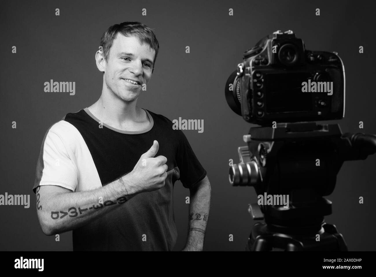 Portrait of man vlogging with camera against gray background Stock ...