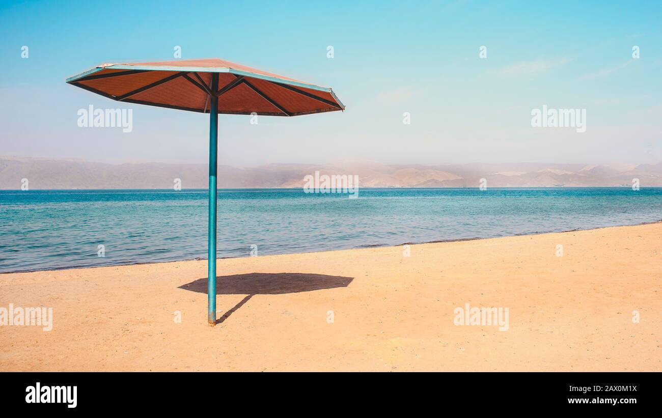 Beach side rest chairs and umbrellas on the sand near the blue water ...
