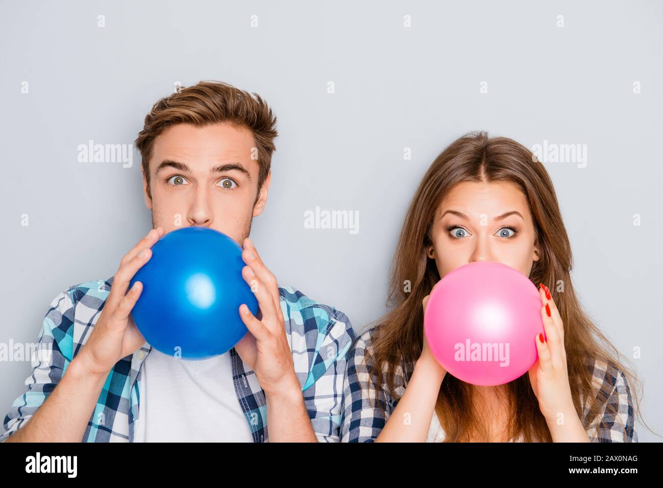 Portrait of happy young man and woman inflating balloons Stock Photo ...