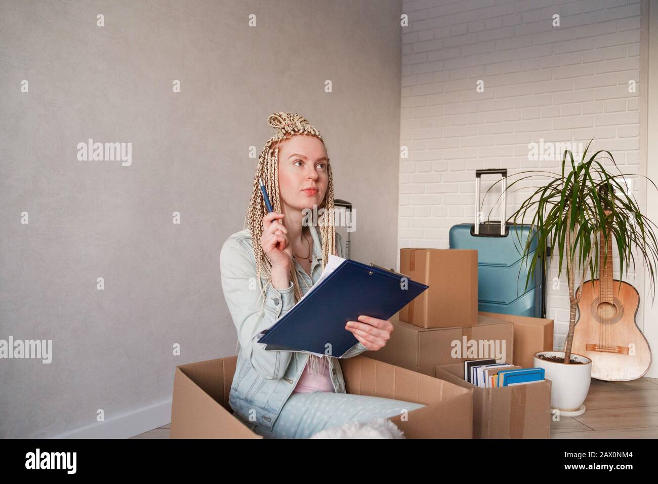Beautiful woman sitting in box in casual clothes is packing her stuff ...