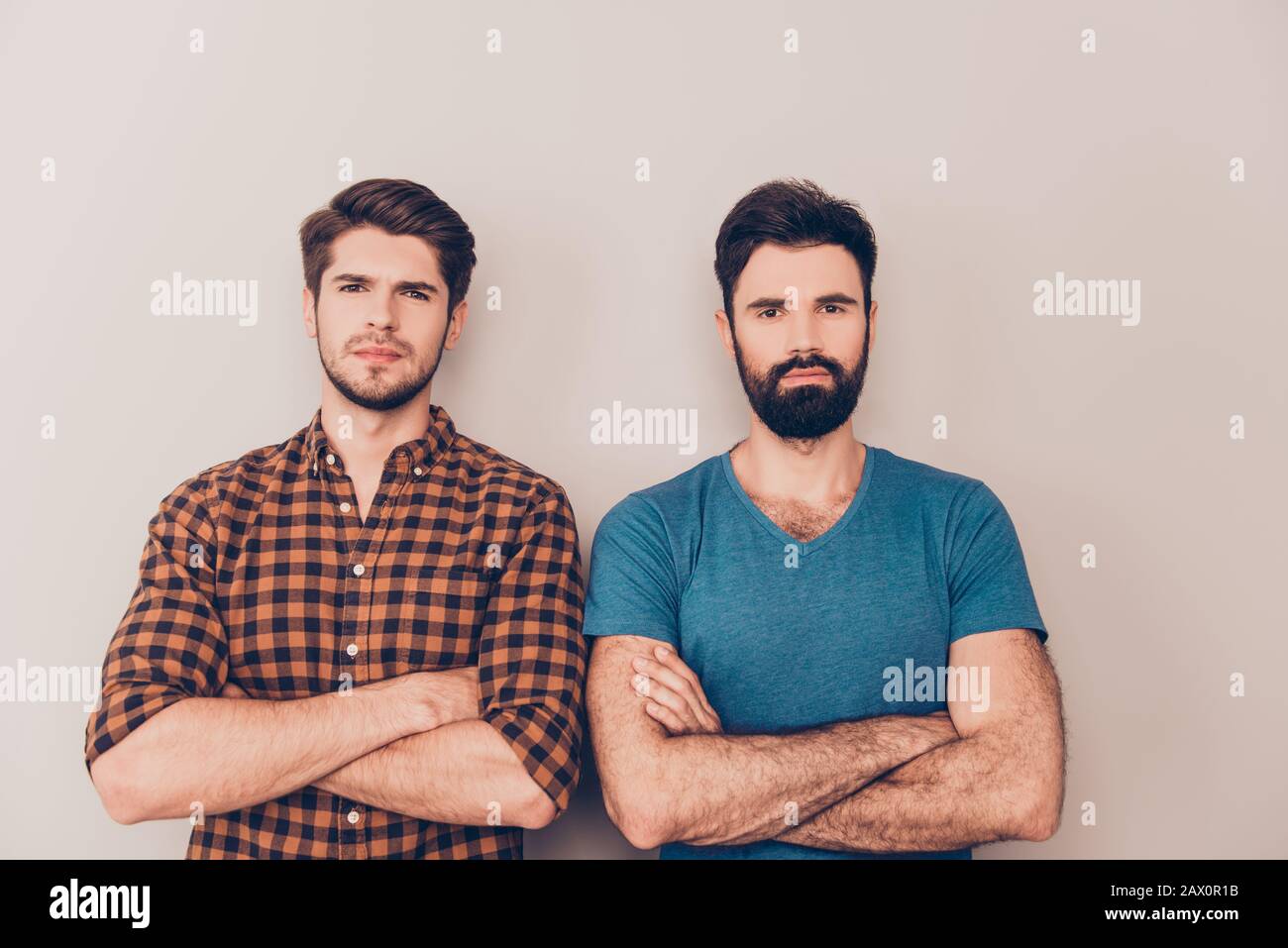 two handsome serious men cross hands while standing gray background ...