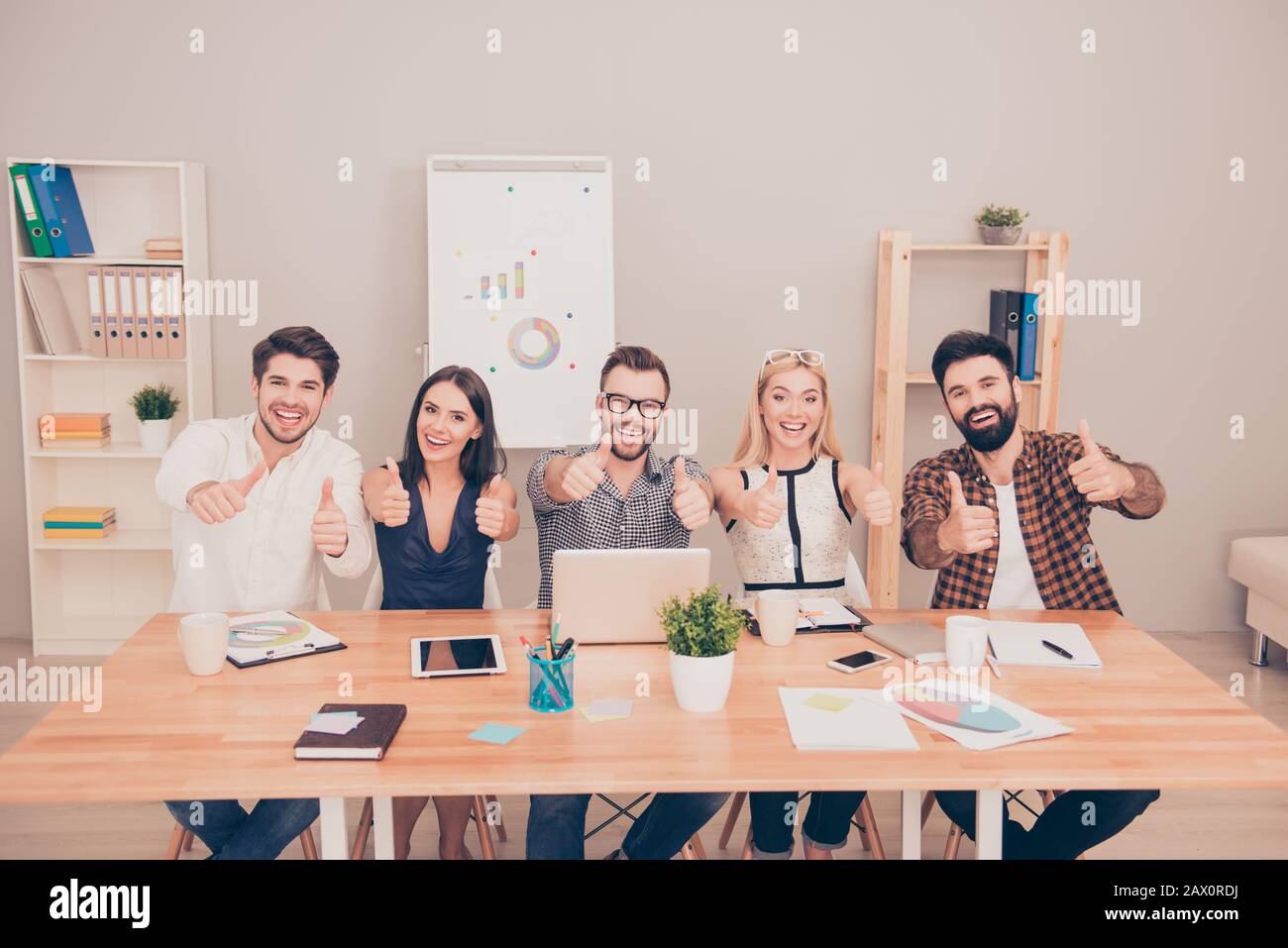 photo of happy young team sitting at conference table smiling and thumb ...