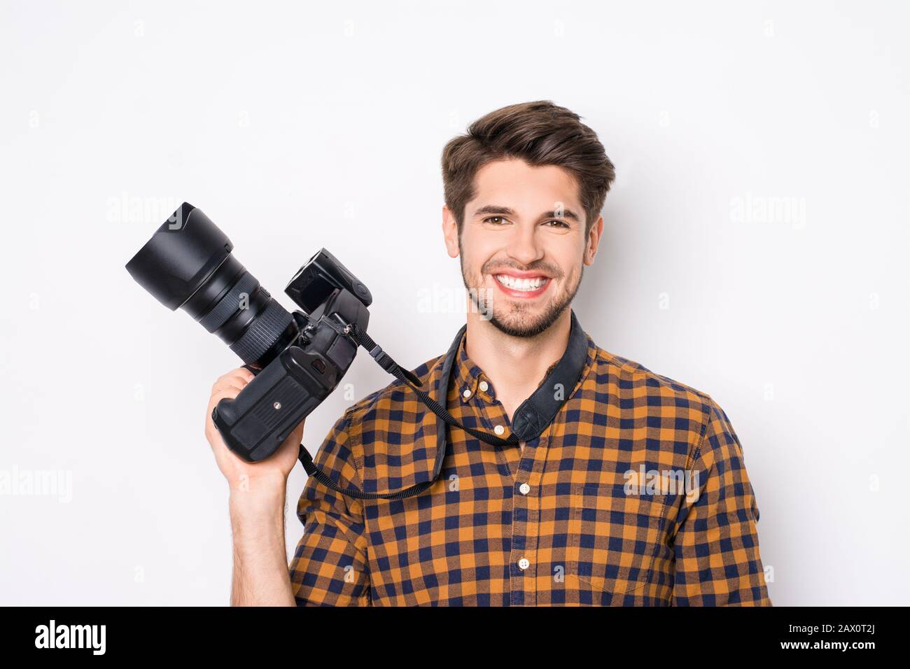 Young cheerful photographer holding camera while working in studio ...