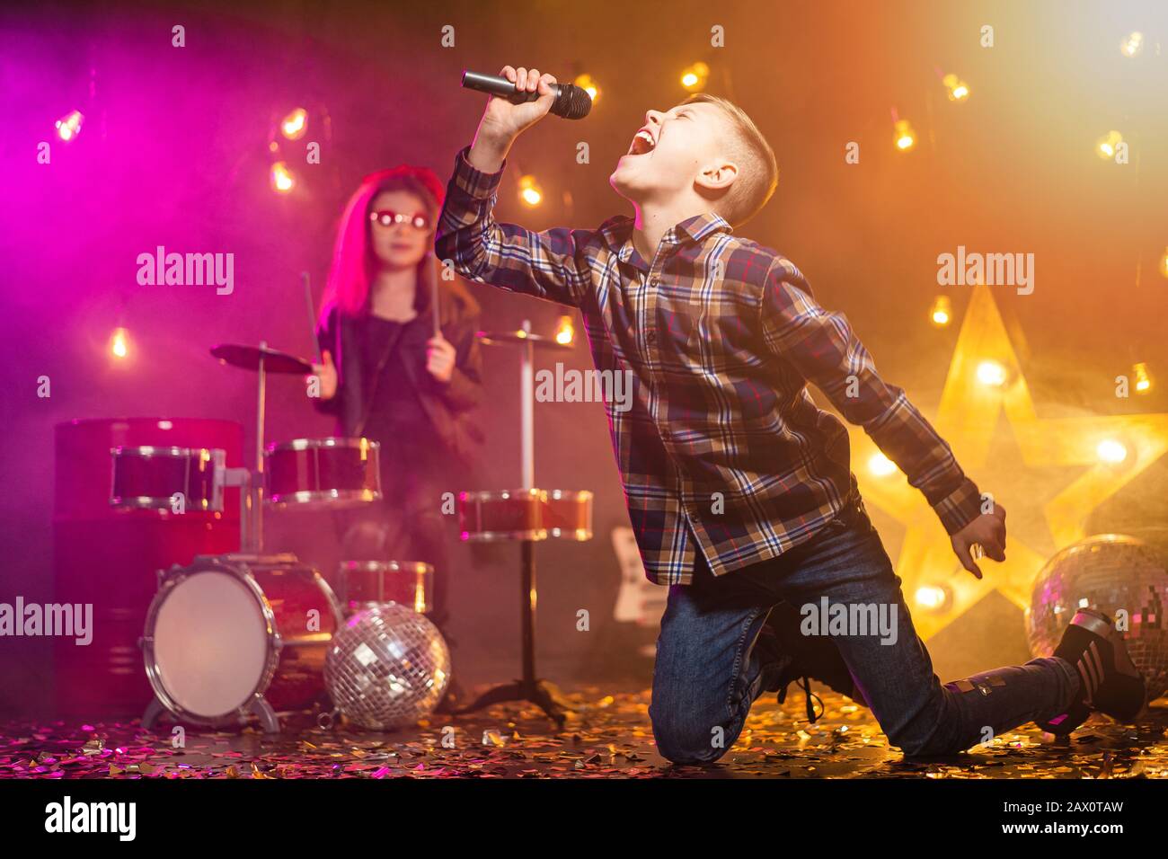 Kids pretending to be a rock band play and sing at studio or stage. Boy ...