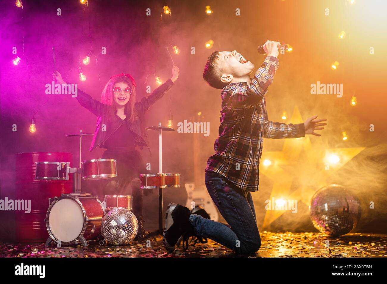 Kids pretending to be a rock band play and sing at studio or stage. Boy ...