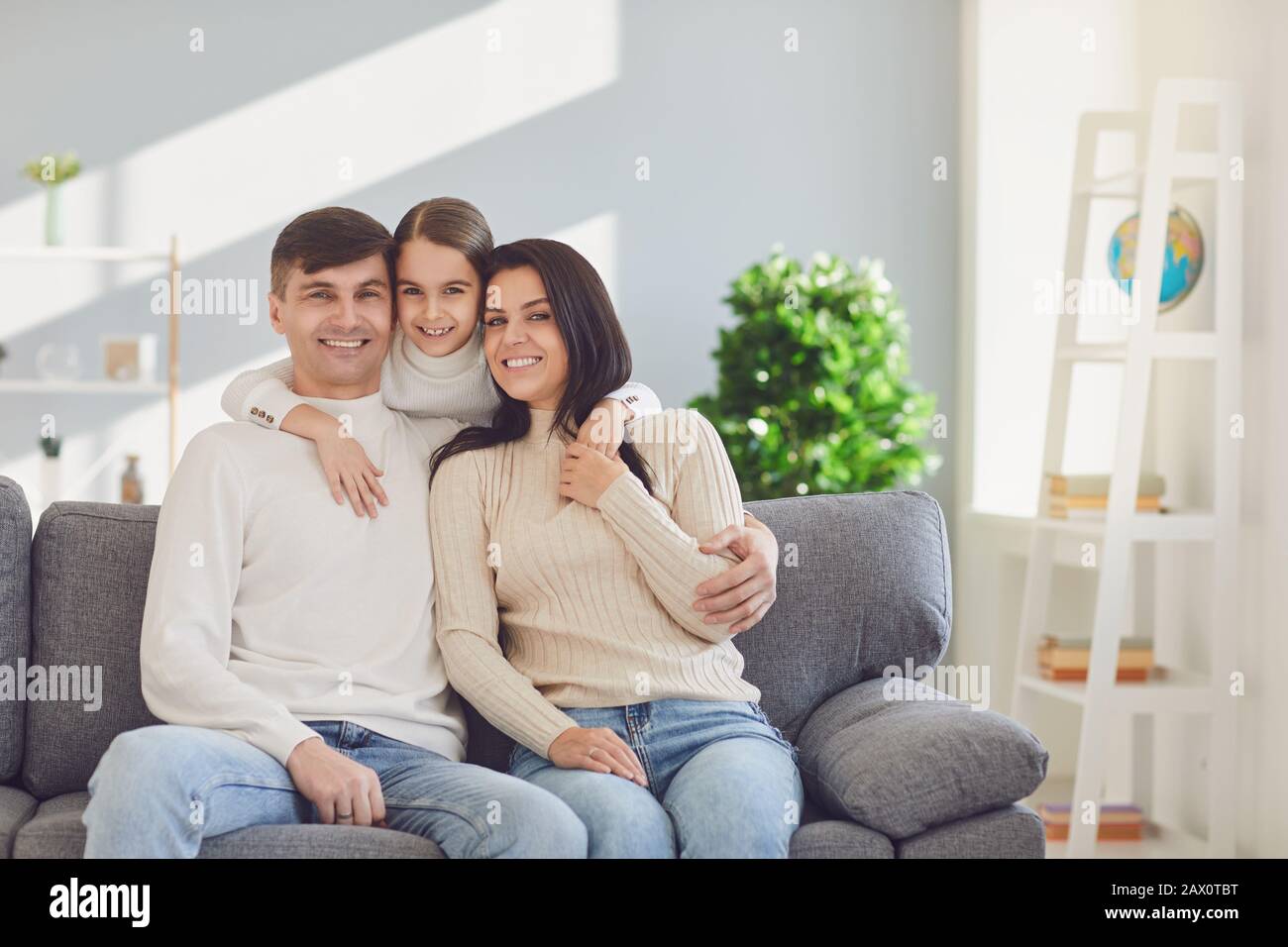 Happy family at home. Mother father and daughter sitting on sofa in ...