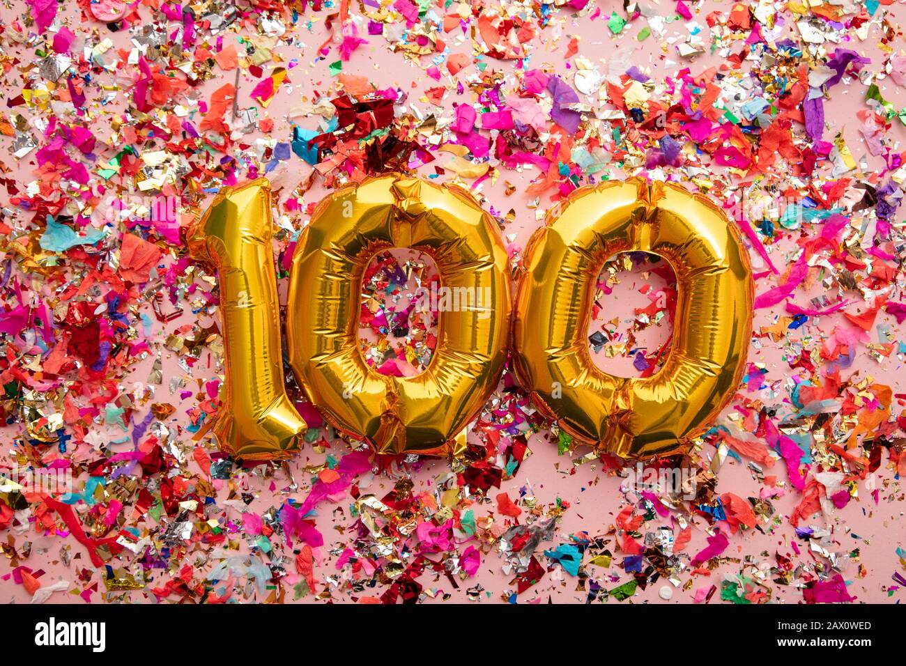 Number 100 gold birthday celebration balloon on a confetti glitter ...