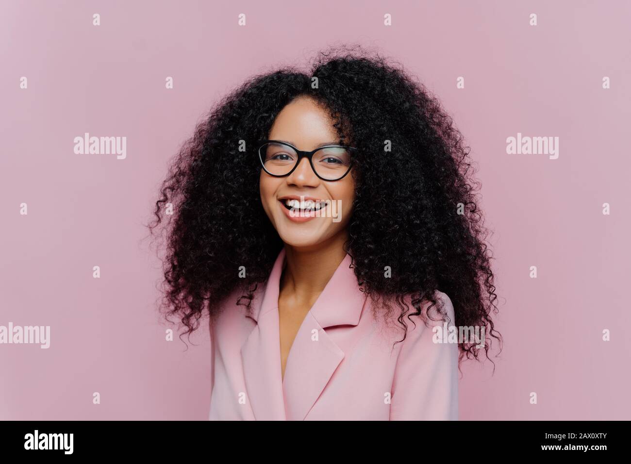 Positive curly haired businesswoman wears spectacles, formal wear, has ...