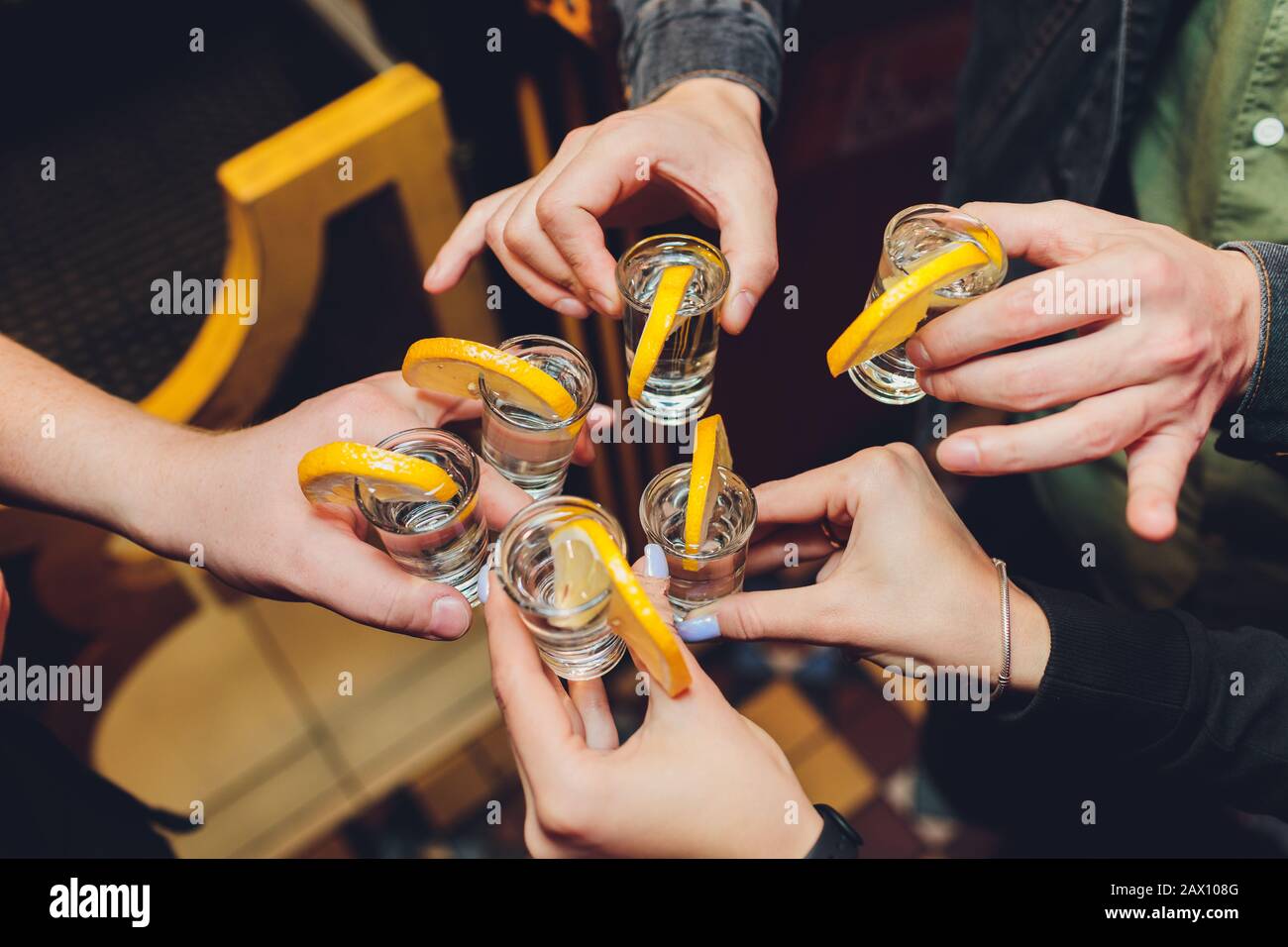 Friends toasting with shot glasses above an old wooden table black ...