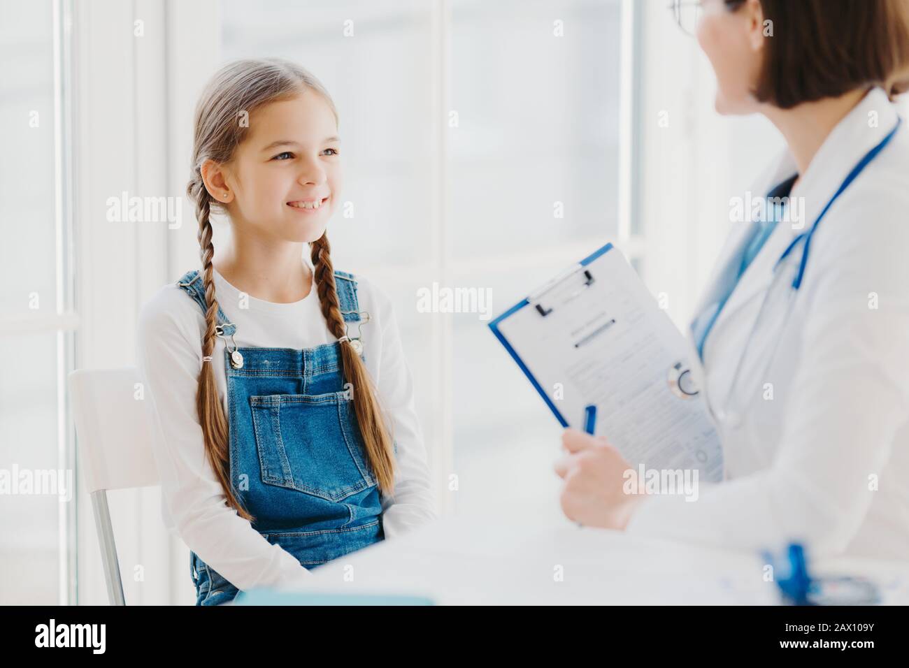 Happy little child listens attentively doctors advice and prescription ...