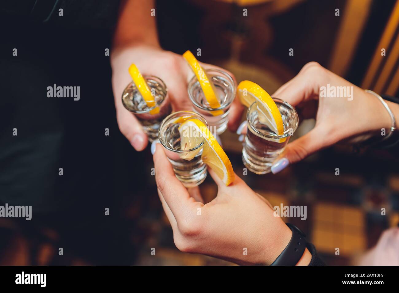 Friends toasting with shot glasses above an old wooden table black ...