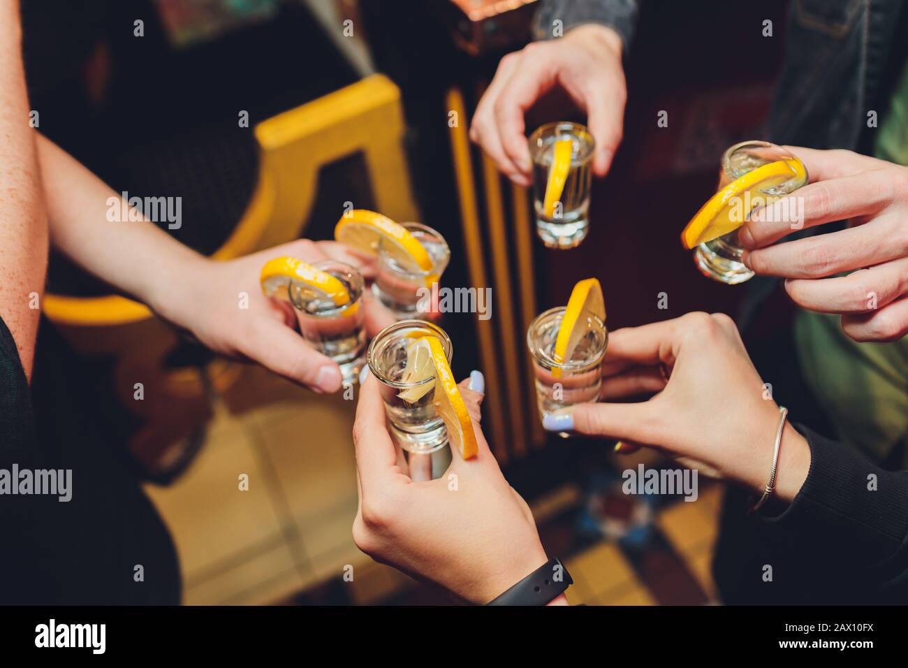 Friends toasting with shot glasses above an old wooden table black ...