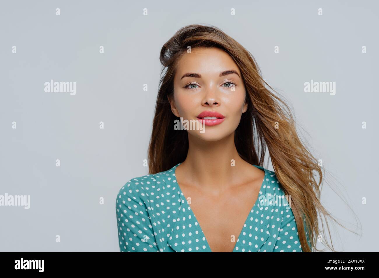 Portrait of pleasant looking young woman looks calmly at camera, has ...