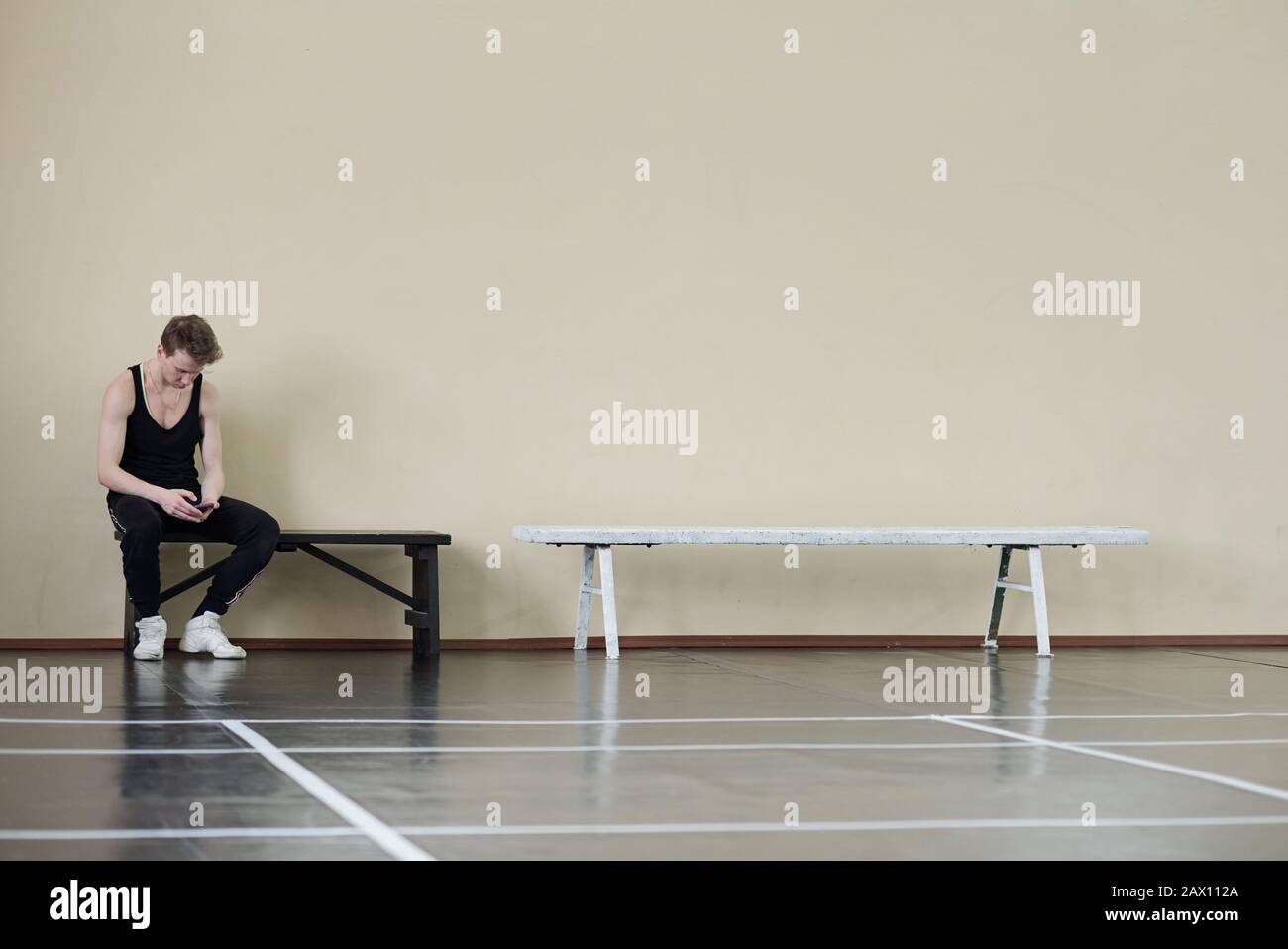 Horiozntal long shot of young man wearing black clothes sitting on ...