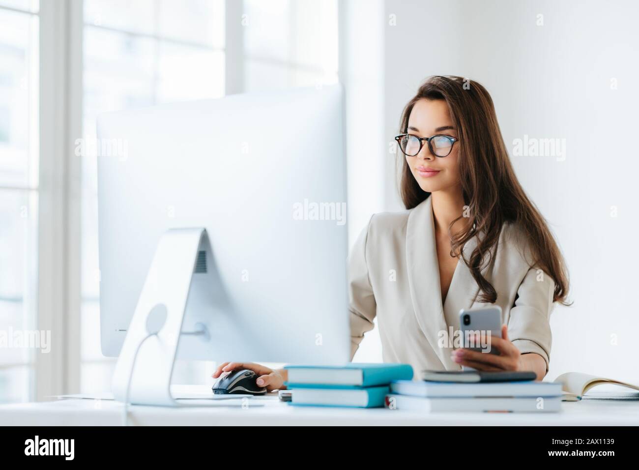 Pretty female entrepreneur with long dark hair, works on computer ...