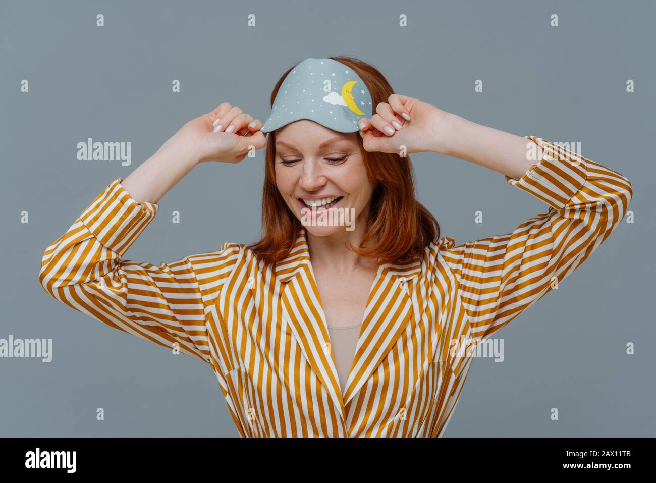 Time to sleep or go to bed. Glad ginger woman keeps gaze down, wears ...